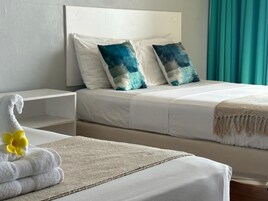 Quarto de hotel com uma cama, mesa de cabeceira, toalha com flor e manta.