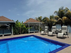 Piscina com espreguiçadeiras e um gazebo.