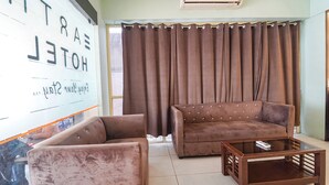 Uma sala de estar com um sofá marrom, uma poltrona combinando e uma mesa de centro de vidro.