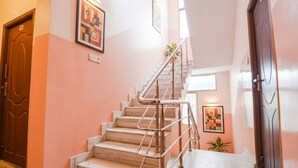 Uma escadaria com grades de metal, uma porta de madeira e uma parede com obras de arte emolduradas.