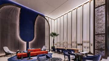 Um hall moderno com área de estar central, bar e grande painel decorativo.