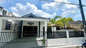 Uma casa residencial com portão fechado, varanda coberta e telhado em telhas.