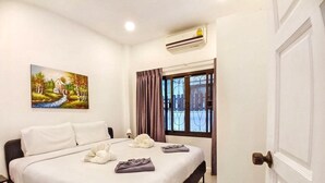 Quarto de hotel com cama, ar condicionado, janela com cortinas e um quadro na parede.