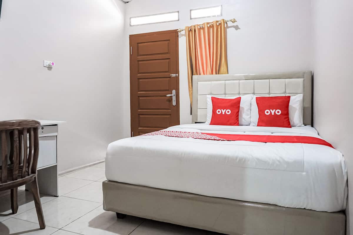 Um quarto com uma cama, uma escrivaninha e uma cadeira.
