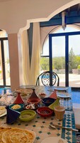 Uma mesa de jantar com diversos pratos e vista para uma piscina e vegetação.
