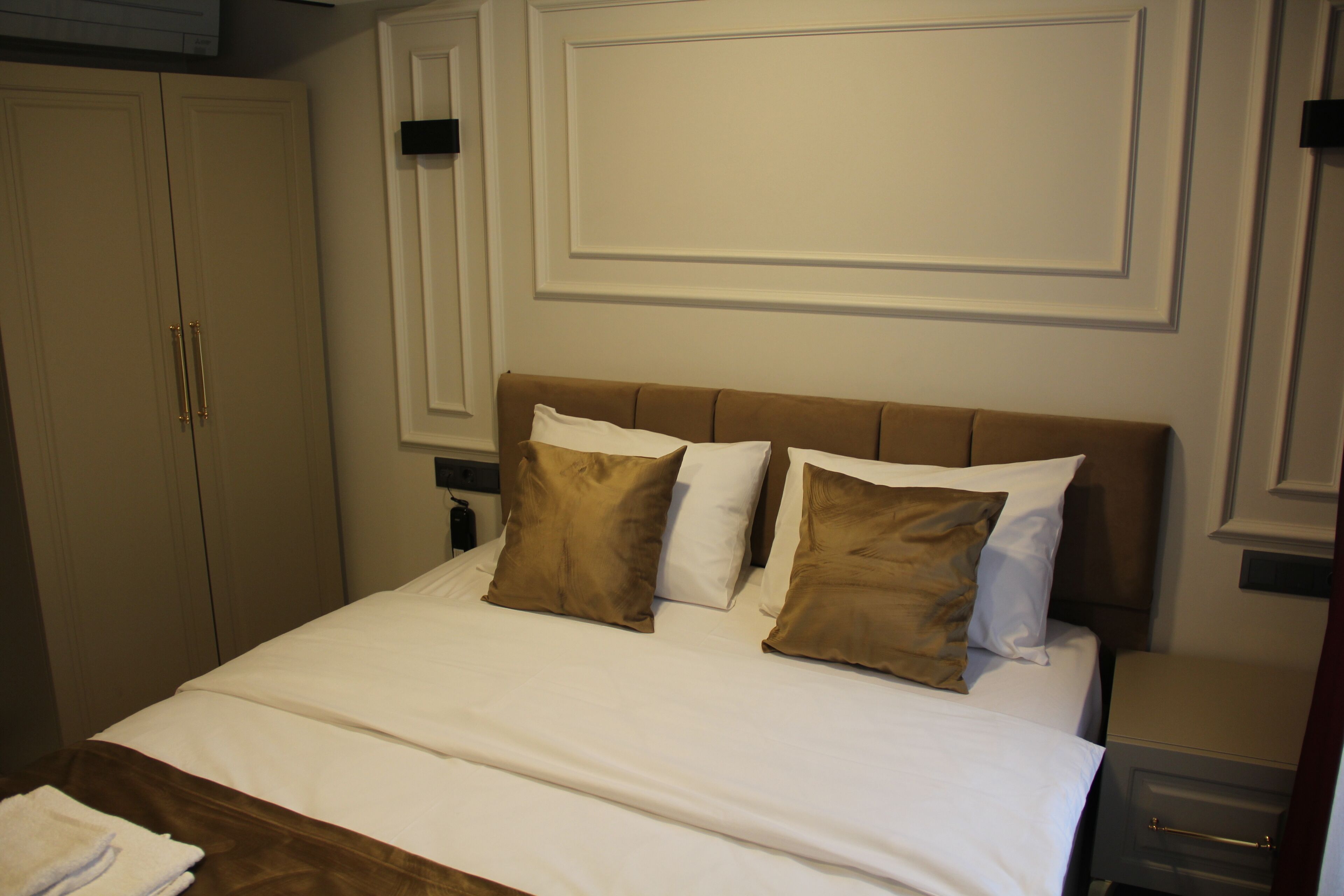 Quarto de hotel com uma cama, mesa de cabeceira e guarda-roupa.
