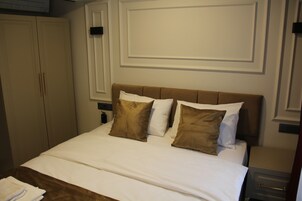 Quarto de hotel com uma cama, mesa de cabeceira e guarda-roupa.