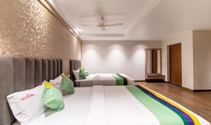Quarto de hotel com uma cama grande, ventoinha no teto e piso de madeira.