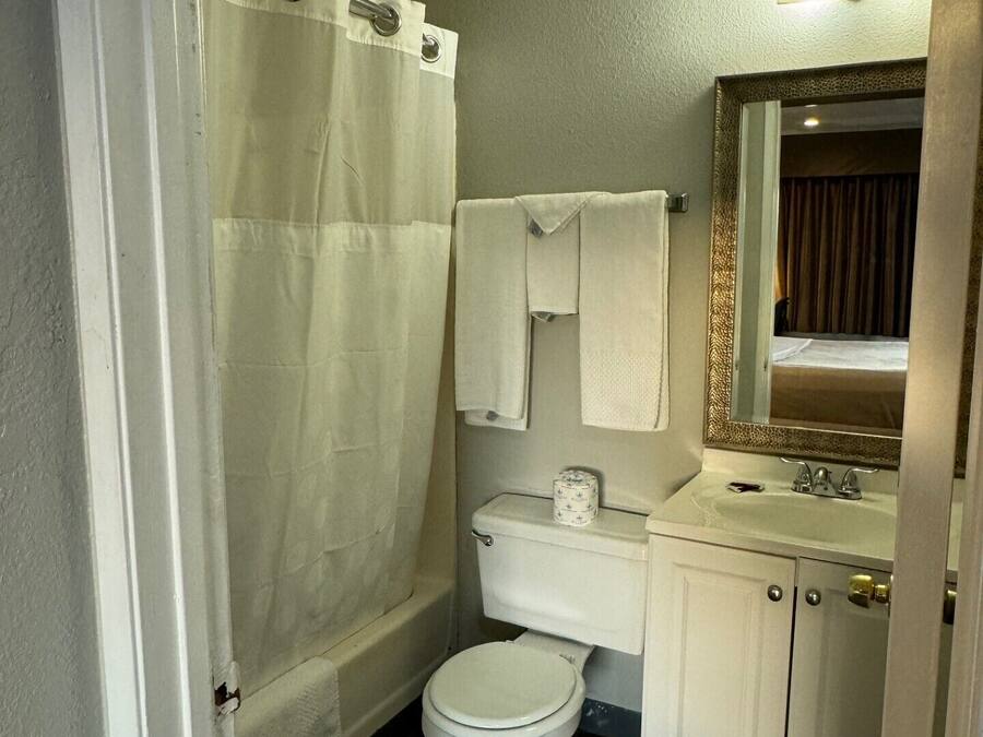 Casa de banho compacta com sanita, lavatório e chuveiro.