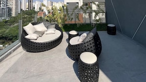 Terraço no telhado com área de estar externa e vista para a cidade.