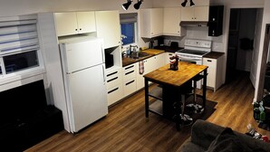 Uma cozinha moderna com armários brancos, uma mesa de jantar de madeira e um forno embutido.