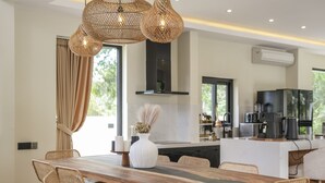 Uma cozinha moderna com mesa de jantar de madeira, cadeiras de vime e iluminação pendente.
