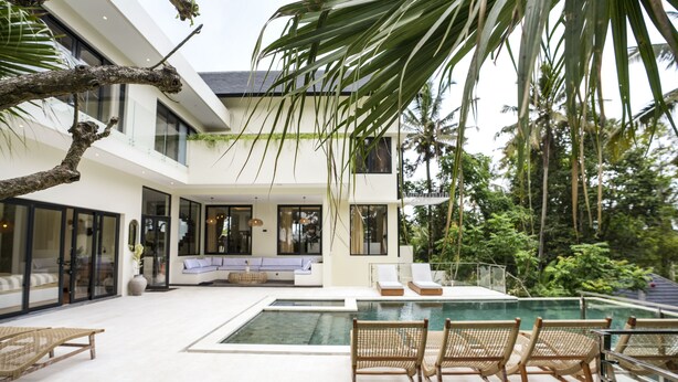 Uma casa moderna com piscina, área de estar externa e vegetação exuberante.