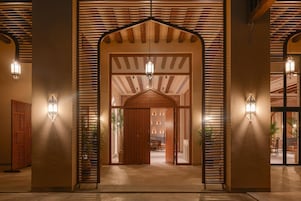 Entrada de hotel com arco de madeira, lanternas e vista para o interior.