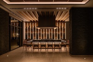 Uma sala de jantar moderna com uma mesa comprida, cadeiras e uma parede decorativa com vasos.