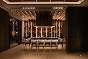 Uma sala de jantar moderna com uma mesa comprida, cadeiras e uma parede decorativa com vasos.