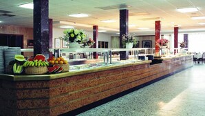 Uma área de buffet com balcão de mármore, diversas frutas e flores.