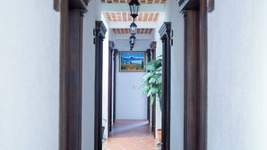 Um corredor com chão de azulejos, teto com padrão de tijolos e luminária pendente.