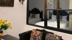 Quarto com cama, janela, ventoinha no teto e plantas penduradas.