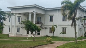 Um edifício grande, de dois andares, com fachada simétrica, várias janelas e uma varanda central.