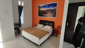 Quarto de hotel com cama, janela com cortinas, um quadro na parede e uma porta.