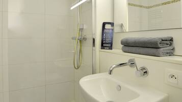 Um chuveiro fixo, toalhas fornecidas, sabão, champô