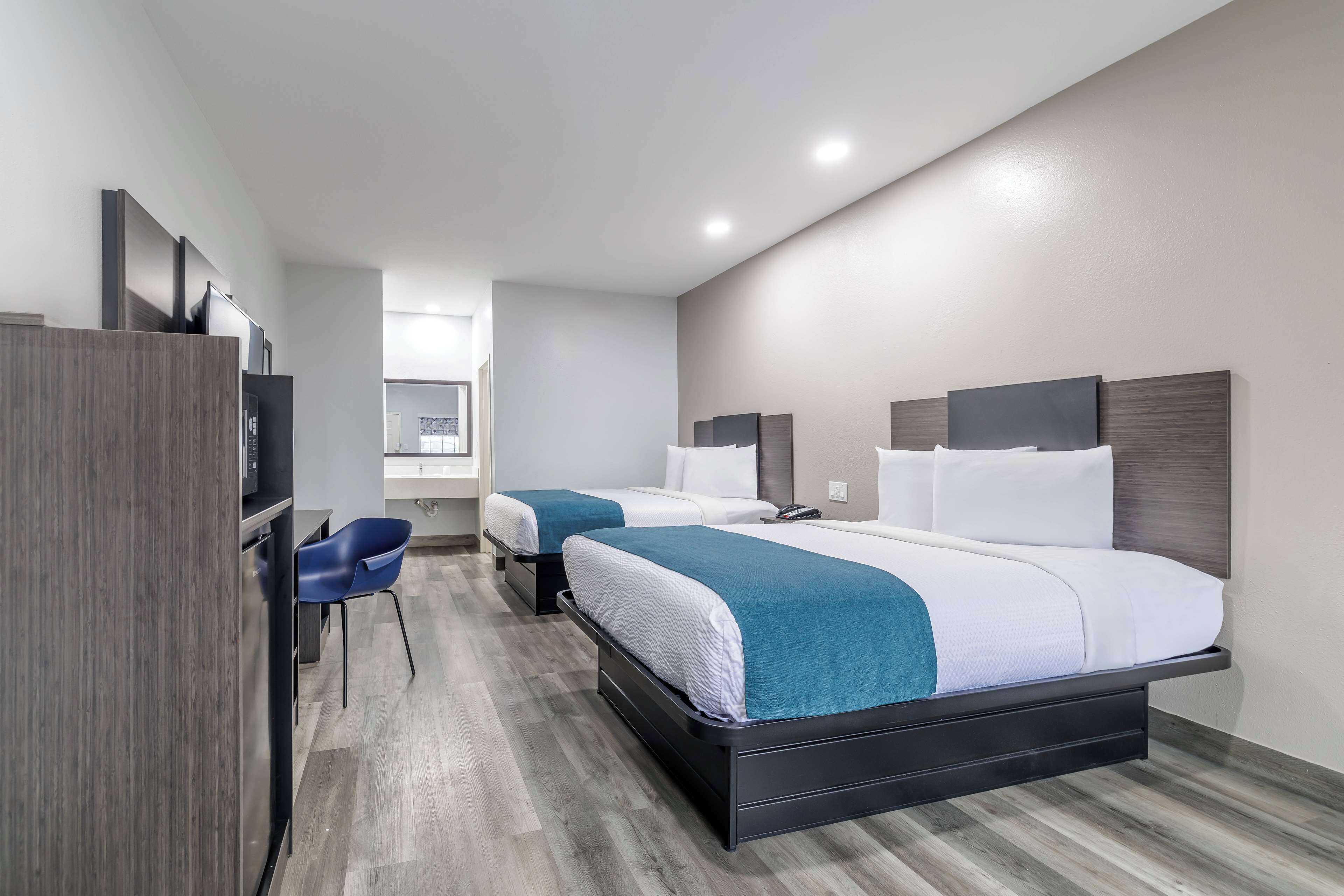Quarto de hotel com duas camas, uma escrivaninha e uma cadeira.