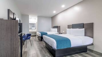 Quarto de hotel com duas camas, uma escrivaninha e uma cadeira.