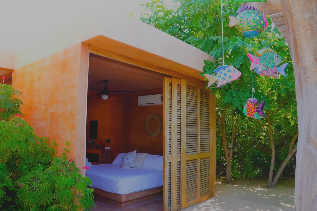 Quarto com cama, ar condicionado e ventoinha no teto.