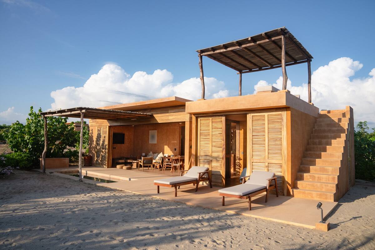 Uma villa moderna com área de pátio, mobiliário para área externa e escada que leva ao andar superior.