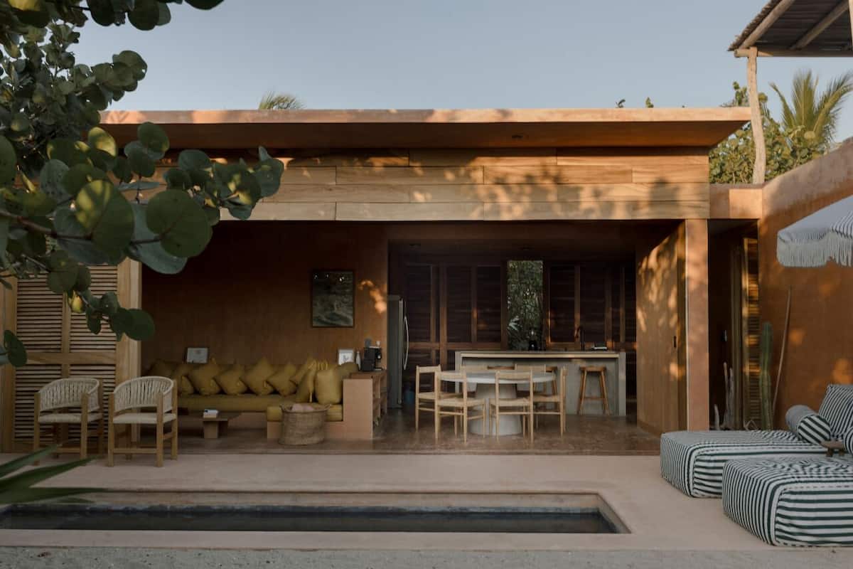 Uma área externa moderna com espaço de estar, mesa e cadeiras, um sofá e uma piscina.