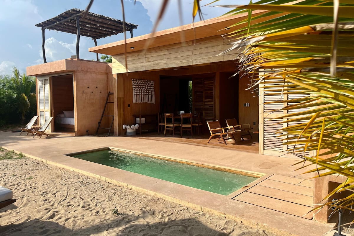 Um edifício moderno com piscina, móveis de madeira e área externa coberta.