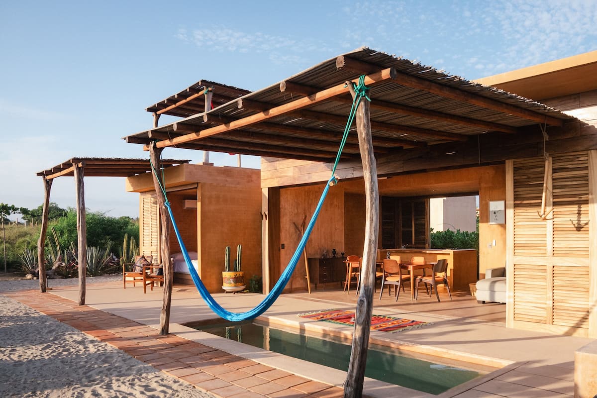 Um pátio moderno ao ar livre com piscina, pérgola de madeira e uma rede.