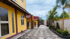 Uma rua estreita com edifícios amarelos, calçada de azulejos e alguma vegetação.
