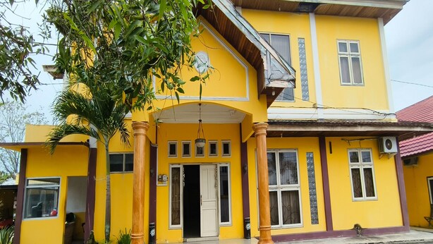 Um edifício amarelo com entrada central, grandes janelas e chão revestido de azulejos.