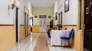 Um corredor com chão de azulejos, uma mesa com cadeiras e uma porta à direita.