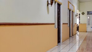 Corredor com piso ladrilhado e portas que dão para os quartos.