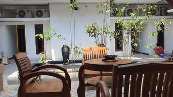 Um pátio amplo com piso de azulejos, móveis de madeira e vários vasos com plantas.