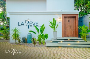 Uma villa moderna com uma porta de madeira e uma placa que diz "LA Rêve The Beach Villa".