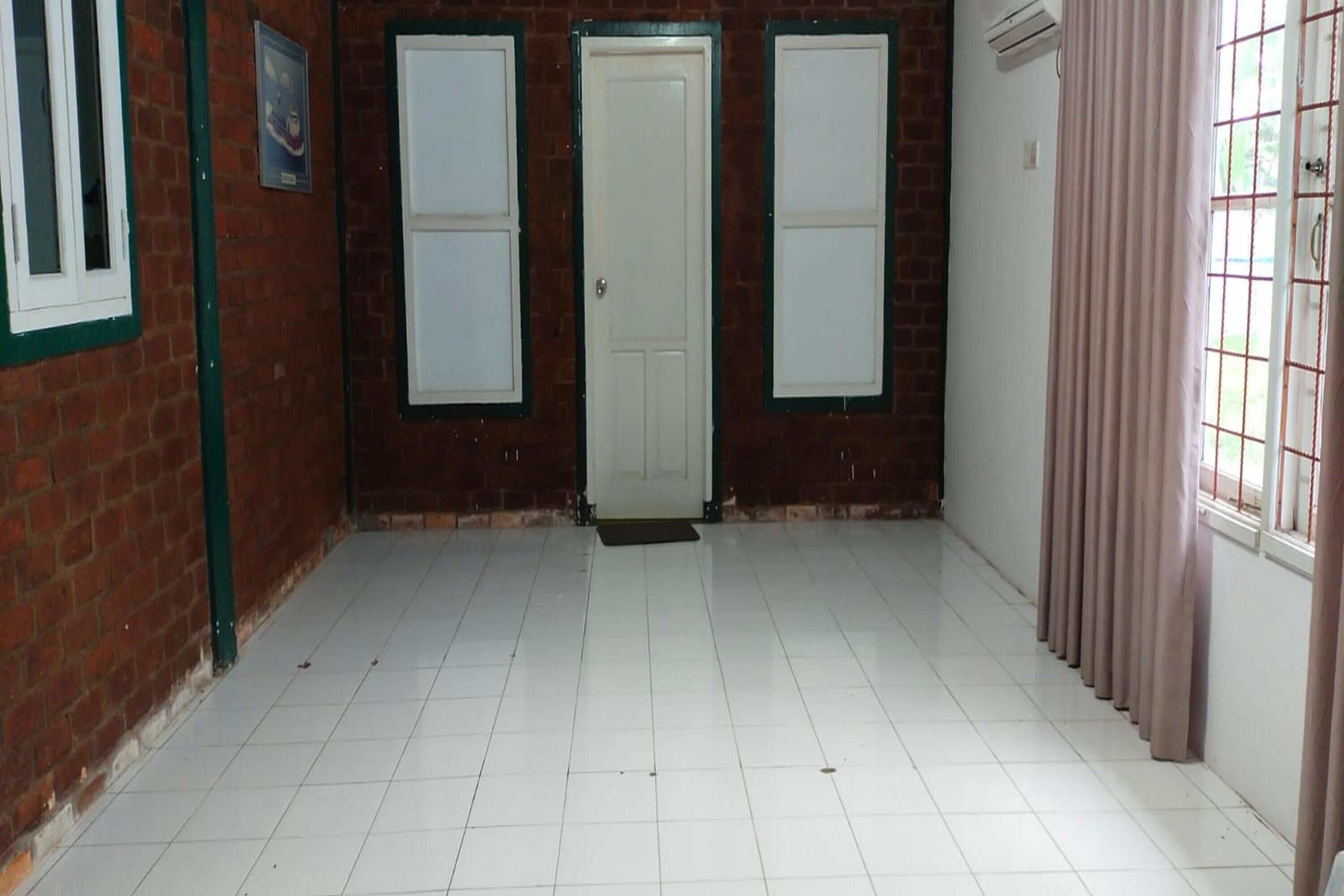 Um corredor com três portas, piso ladrilhado e uma janela com cortinas.