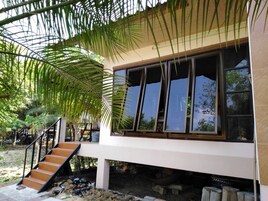 Uma casa moderna com escadaria que dá para uma varanda, cercada por vegetação exuberante.
