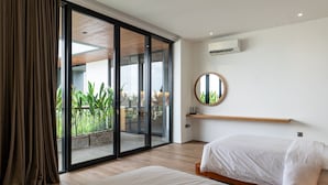 Quarto de hotel moderno com duas camas, uma grande porta de correr de vidro para uma varanda, um espelho redondo e ar condicionado integrado.