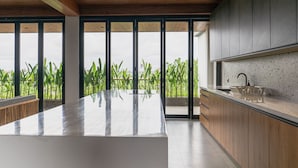 Cozinha moderna com uma ilha grande, armários de madeira e vista para o verde lá fora.