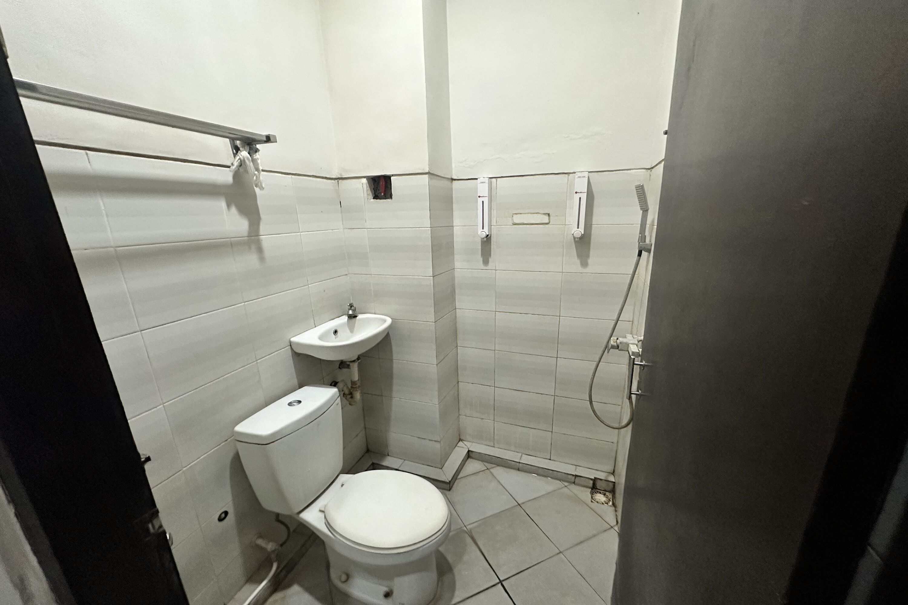 Casa de banho pequena e compacta, com sanita, lavatório e chuveiro.