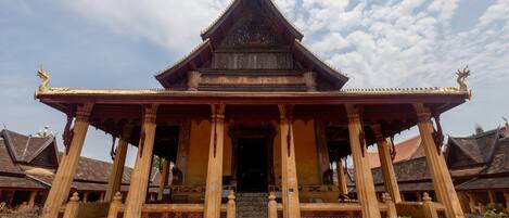 Um templo tradicional com telhado escalonado, colunas ornamentadas e uma entrada central.