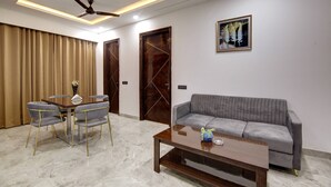 Uma sala de estar moderna com um sofá cinza, uma mesa de centro de madeira e uma mesa de jantar com cadeiras.