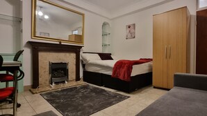 Quarto com cama, guarda-roupa, espelho, lareira e sofá.