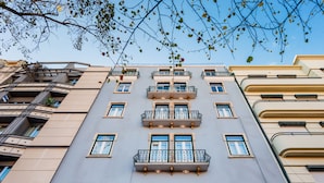 Um edifício com vários andares, varandas, janelas grandes e um céu azul límpido.