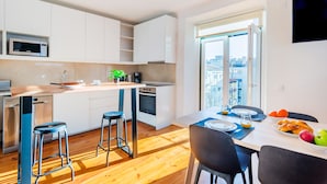 Cozinha moderna com armários brancos, micro-ondas e área de jantar com mesa posta para dois.