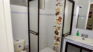 Casa de banho com sanita, cabine de duche e lavatório.